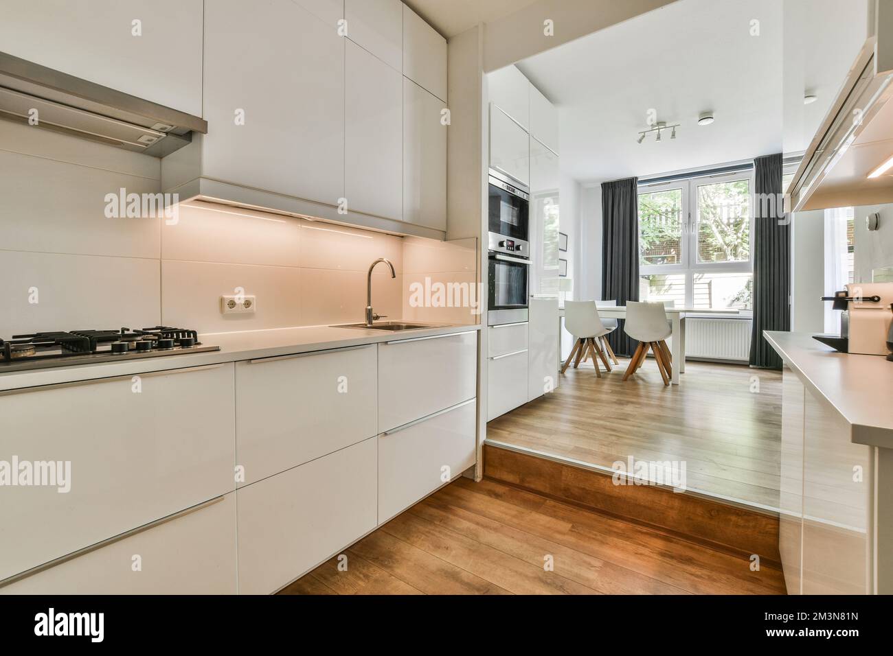 Table with chairs located near lounge area and kitchen in spacious room ...