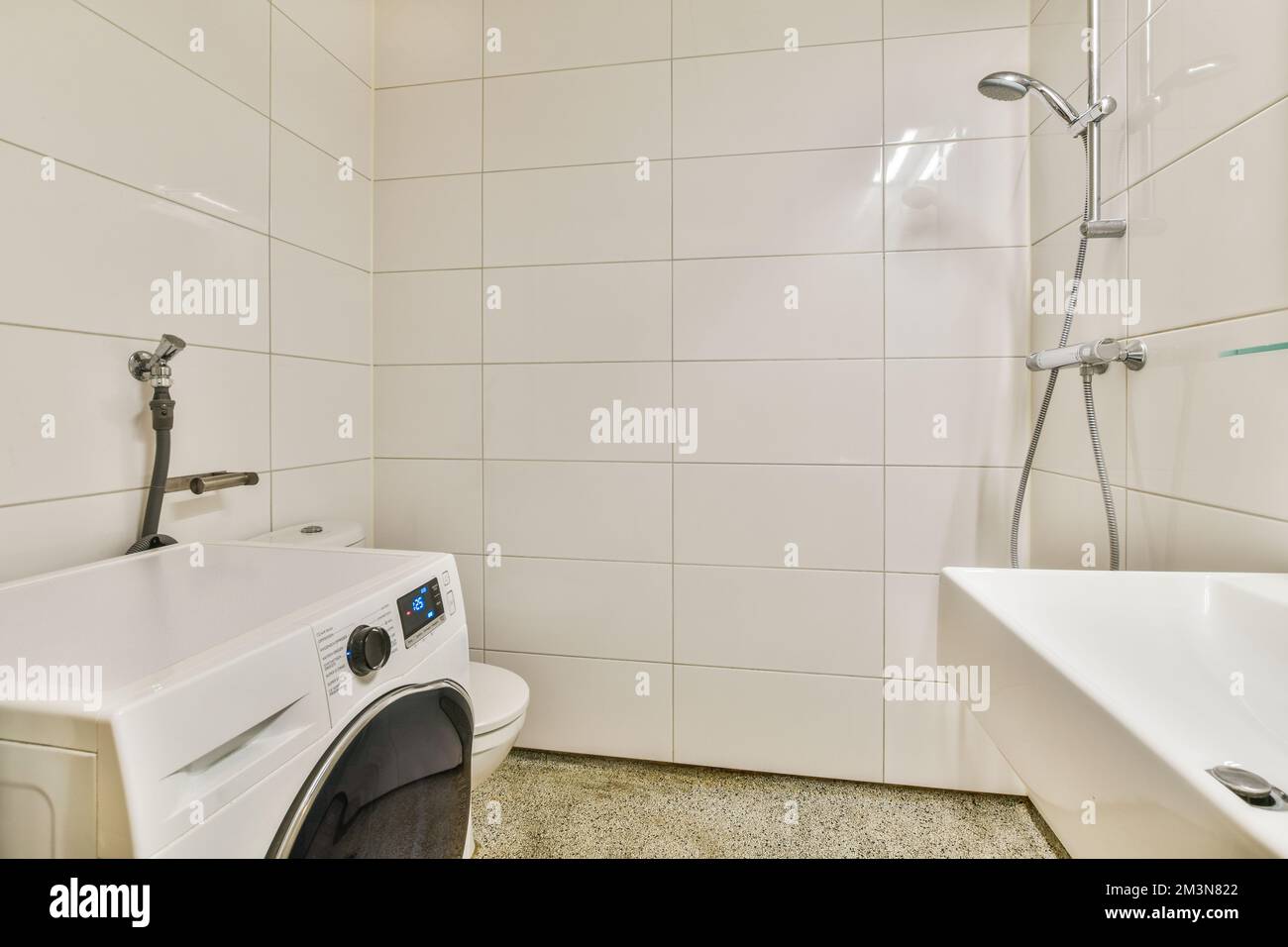 Shower and toilet in light bathroom with washing machine Stock Photo ...