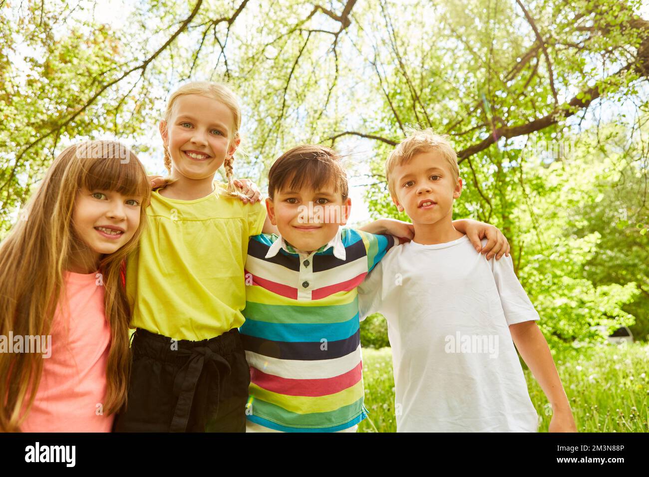 Happy group of children standing together in green garden in summer ...