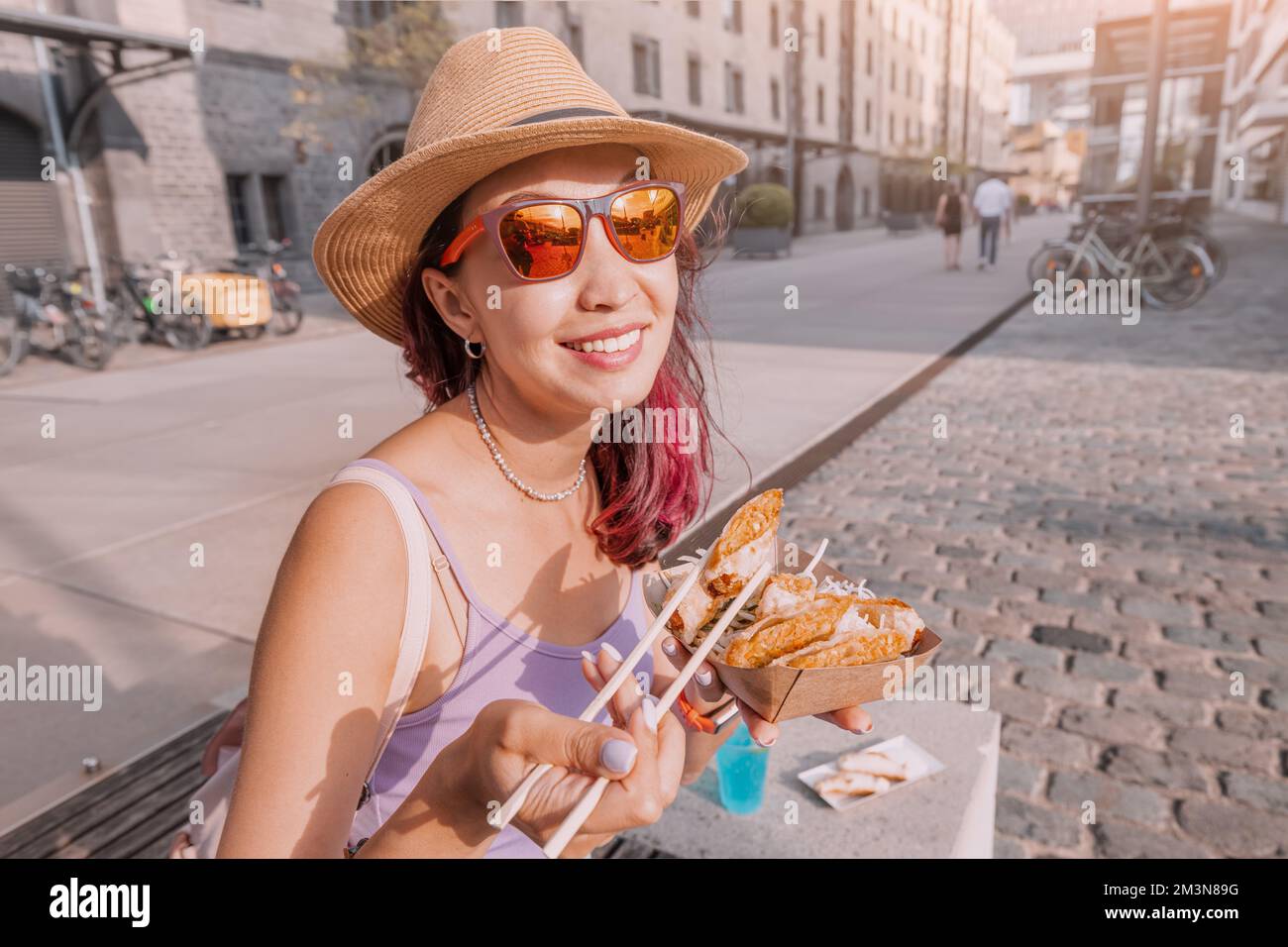Happy cheerful girl eating spring rolls from takeaway paper box using ...
