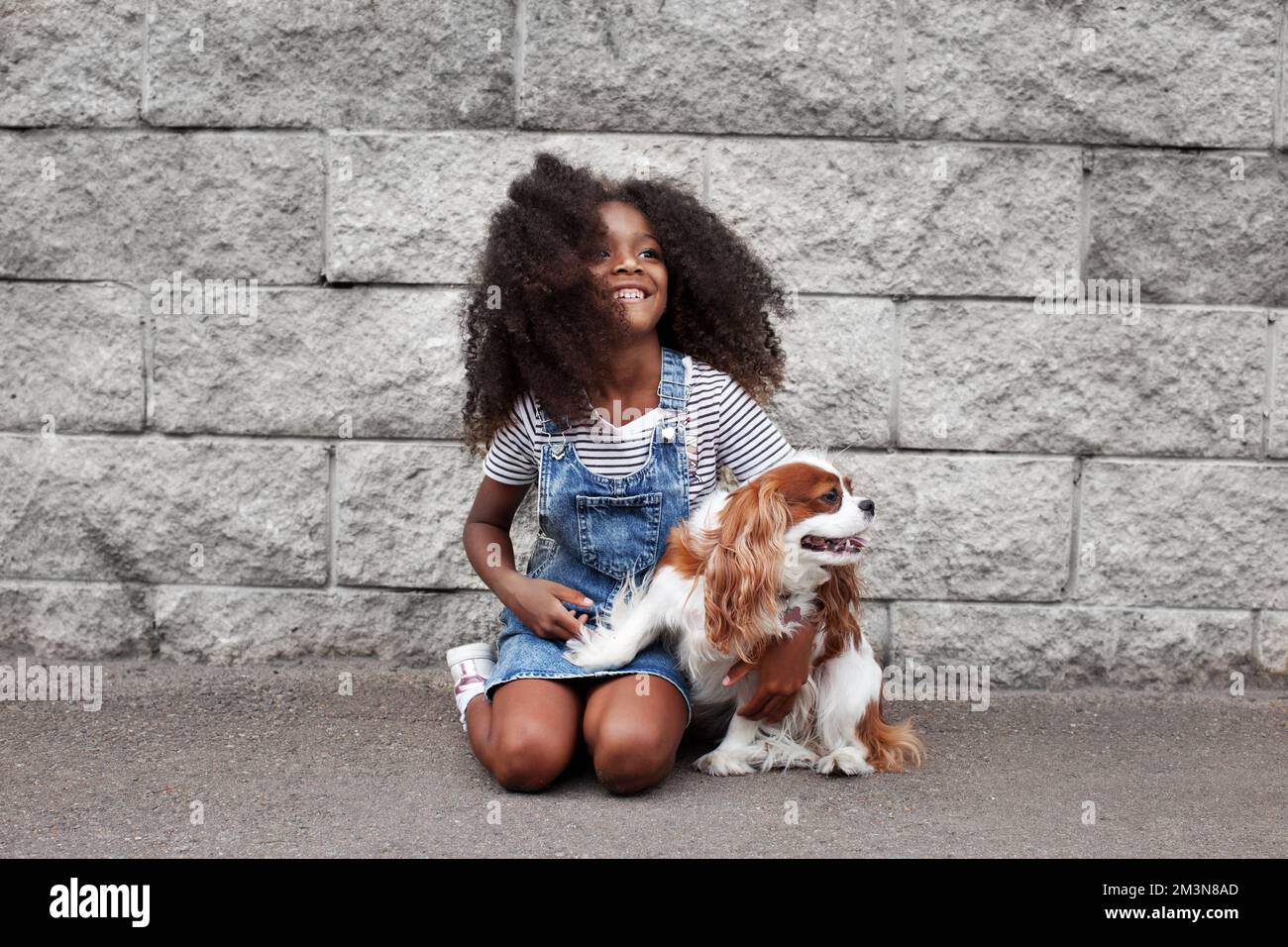 Smiling african american kid girl with dog outside. Happy child with ...