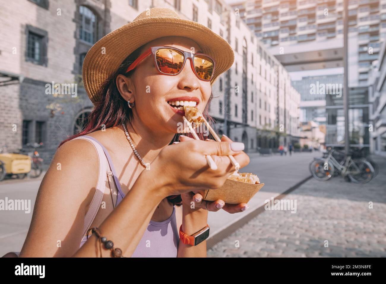 Happy cheerful girl eating spring rolls from takeaway paper box using ...