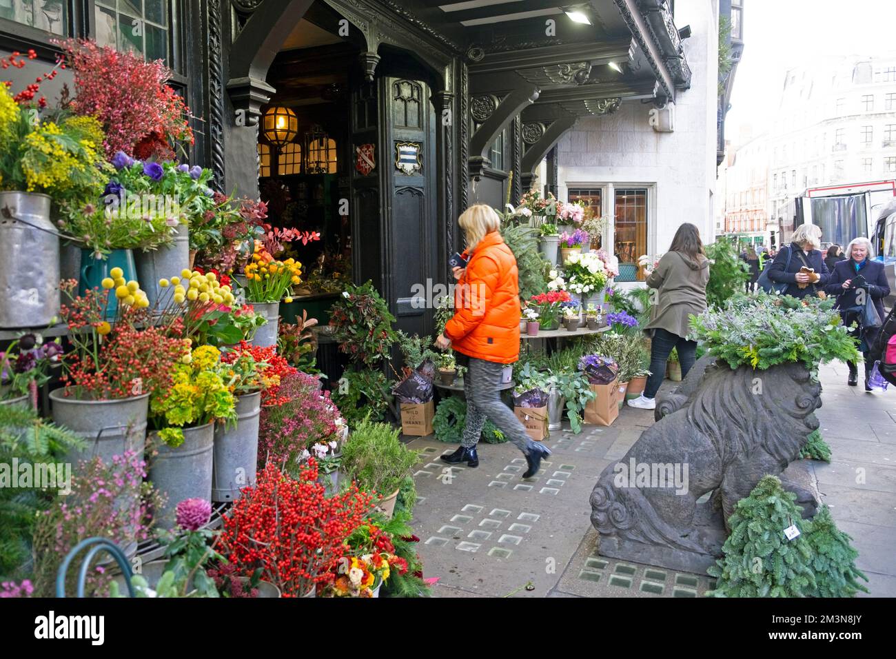 Florist selling cut flowers and woman orange jacket customer entering ...