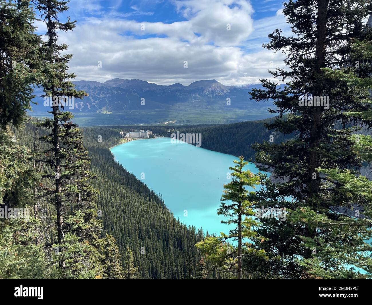 An aerial view of turquoise Lake Louise surrounded by lush green ...