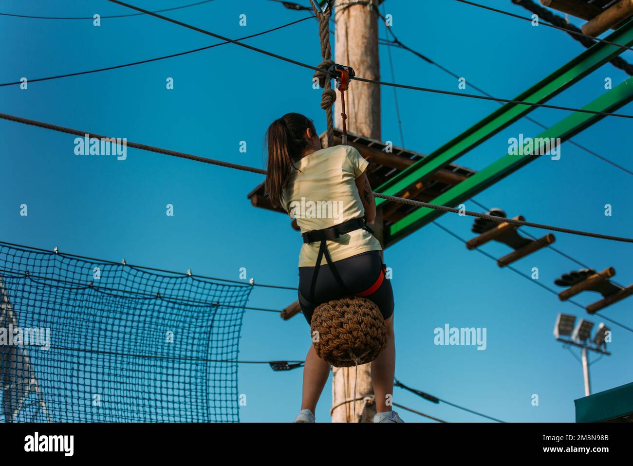 Young woman sitting on a rope sack and going down the zip line Stock ...