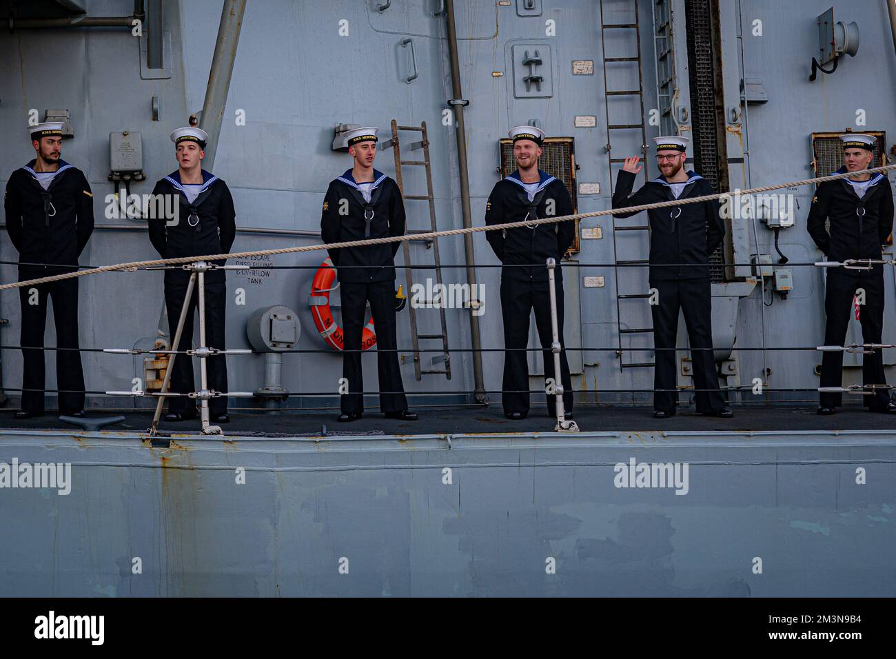 Sailors watch and wave to crowds from the ship's deck as families and ...