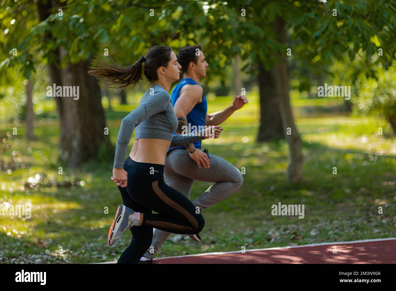 A lovely fit girl is jogging with her boyfriend on a sports track Stock ...
