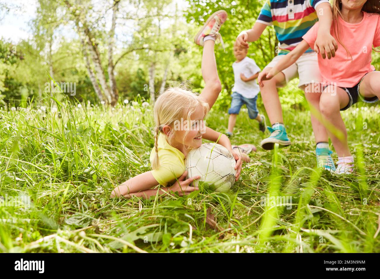 Multiracial children playing soccer and fighting over football in grass ...