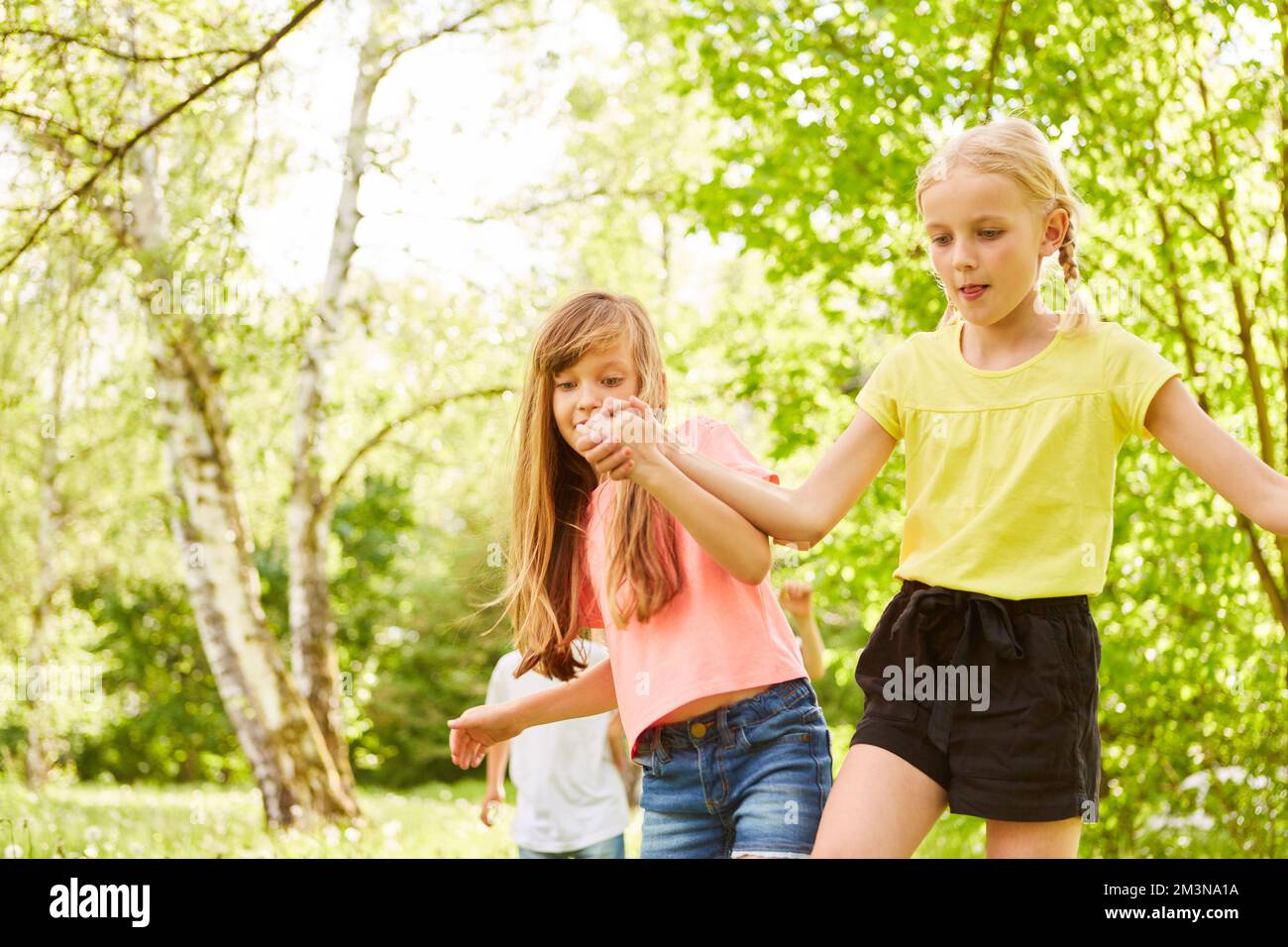Female friends holding hands in three legged race competition at park ...