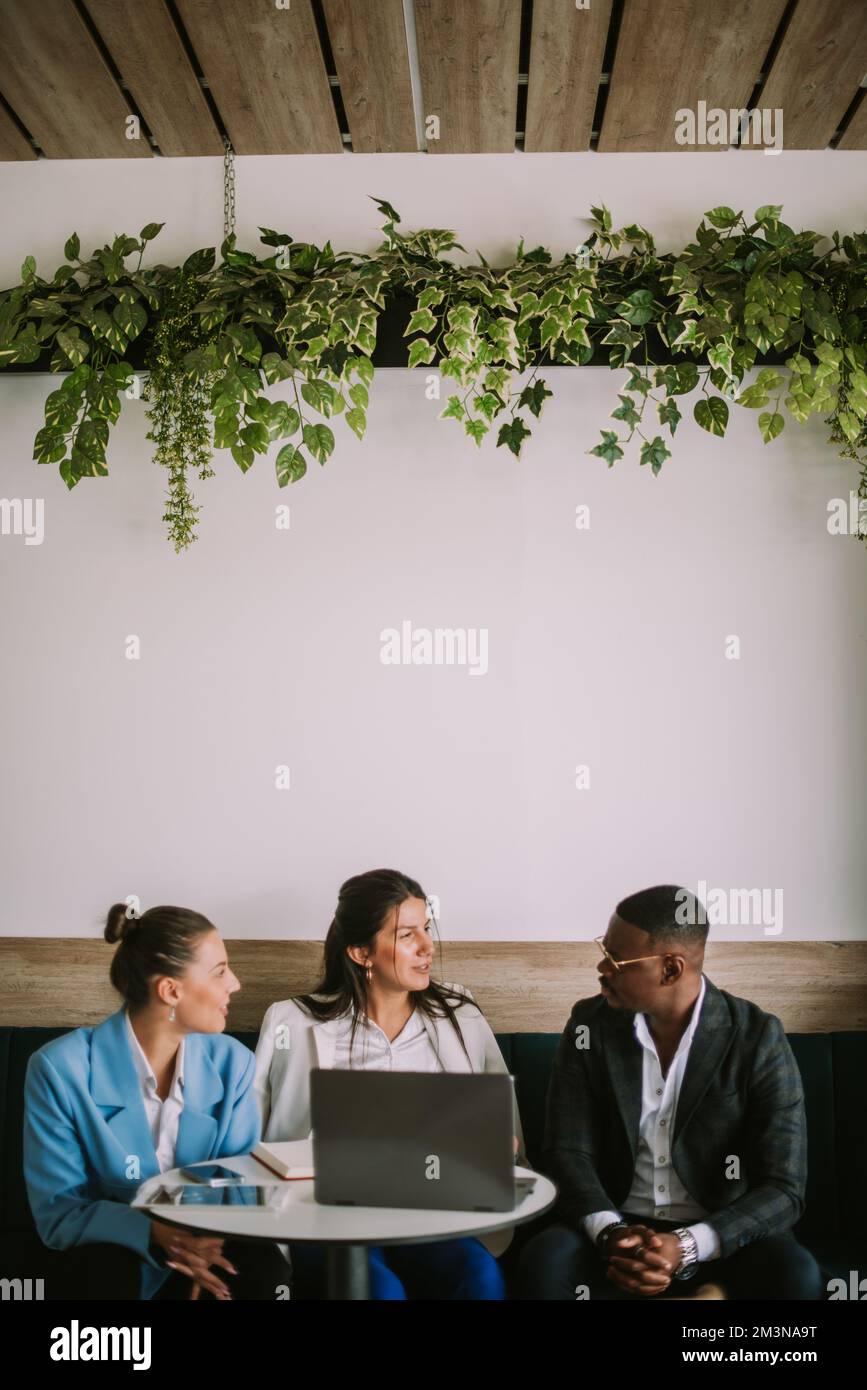 Three business people having a conversation while sitting at the cafe ...