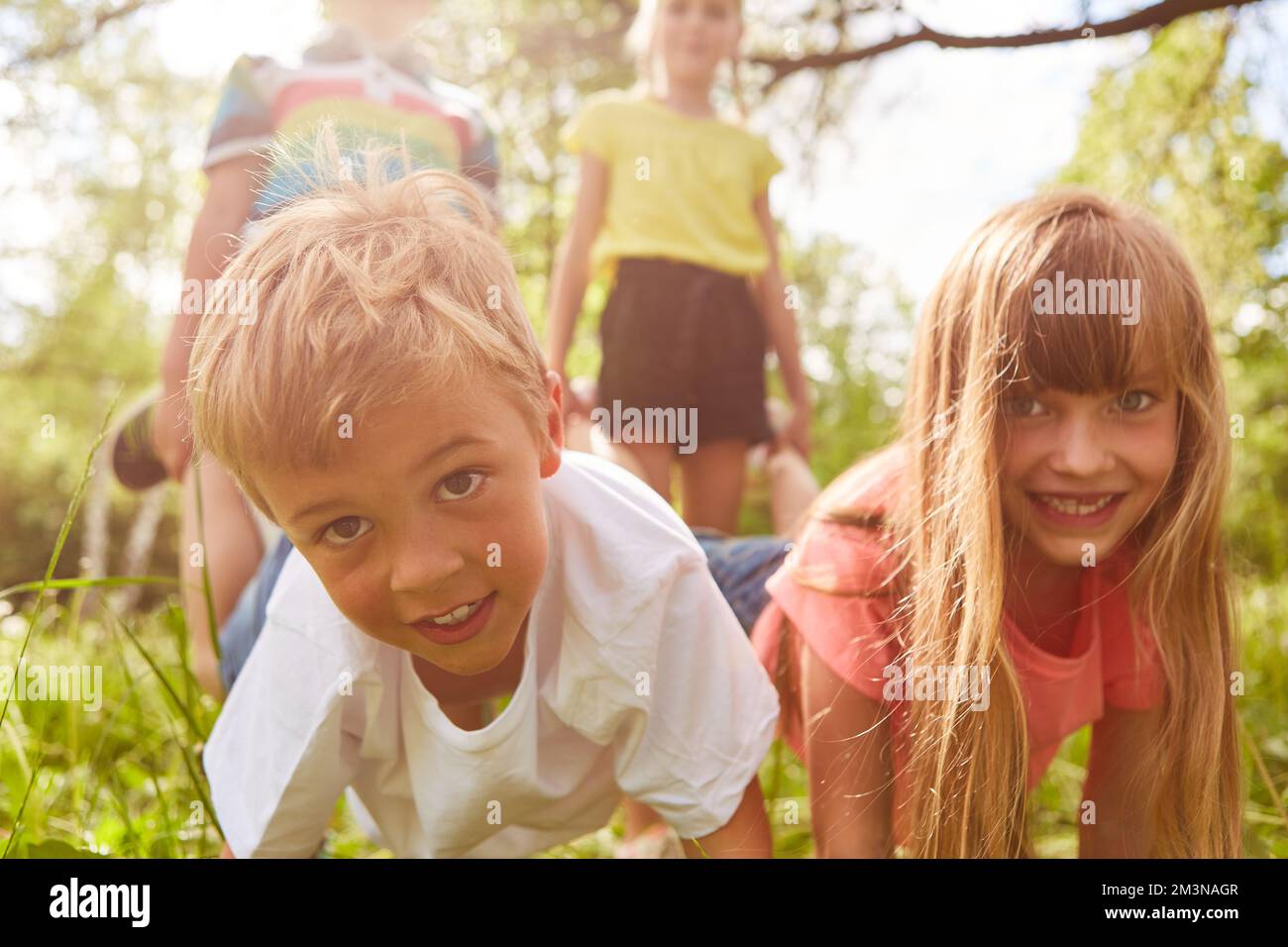 Portrait of happy children competing each other during wheelbarrow race ...