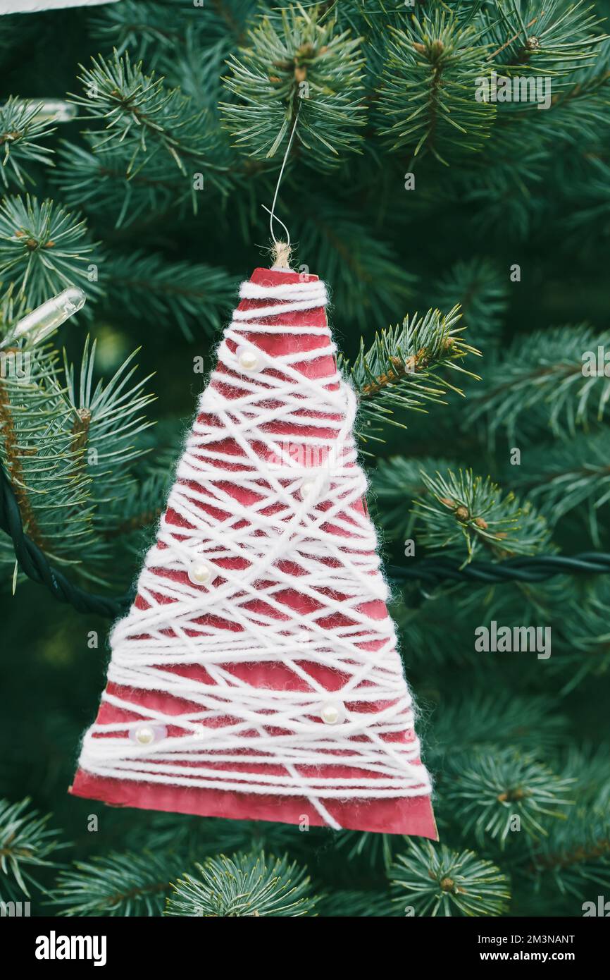 Red wool and paper handmade decoration on Christmas tree outdoor. Diy ...
