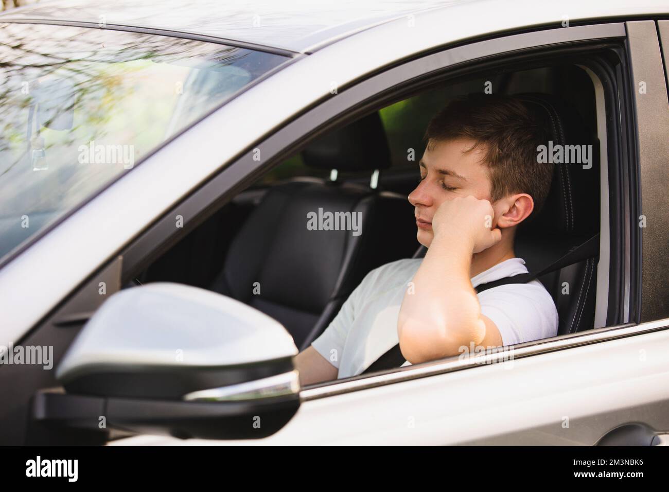 Nearly sleeping yound driver being tired waiting in the traffic jam ...