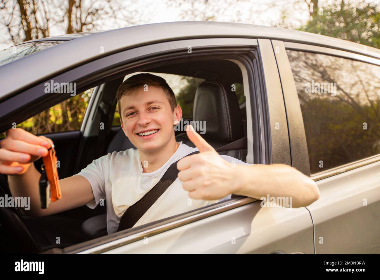 Novice driver holding car keys out of the window, showing thumb up ...