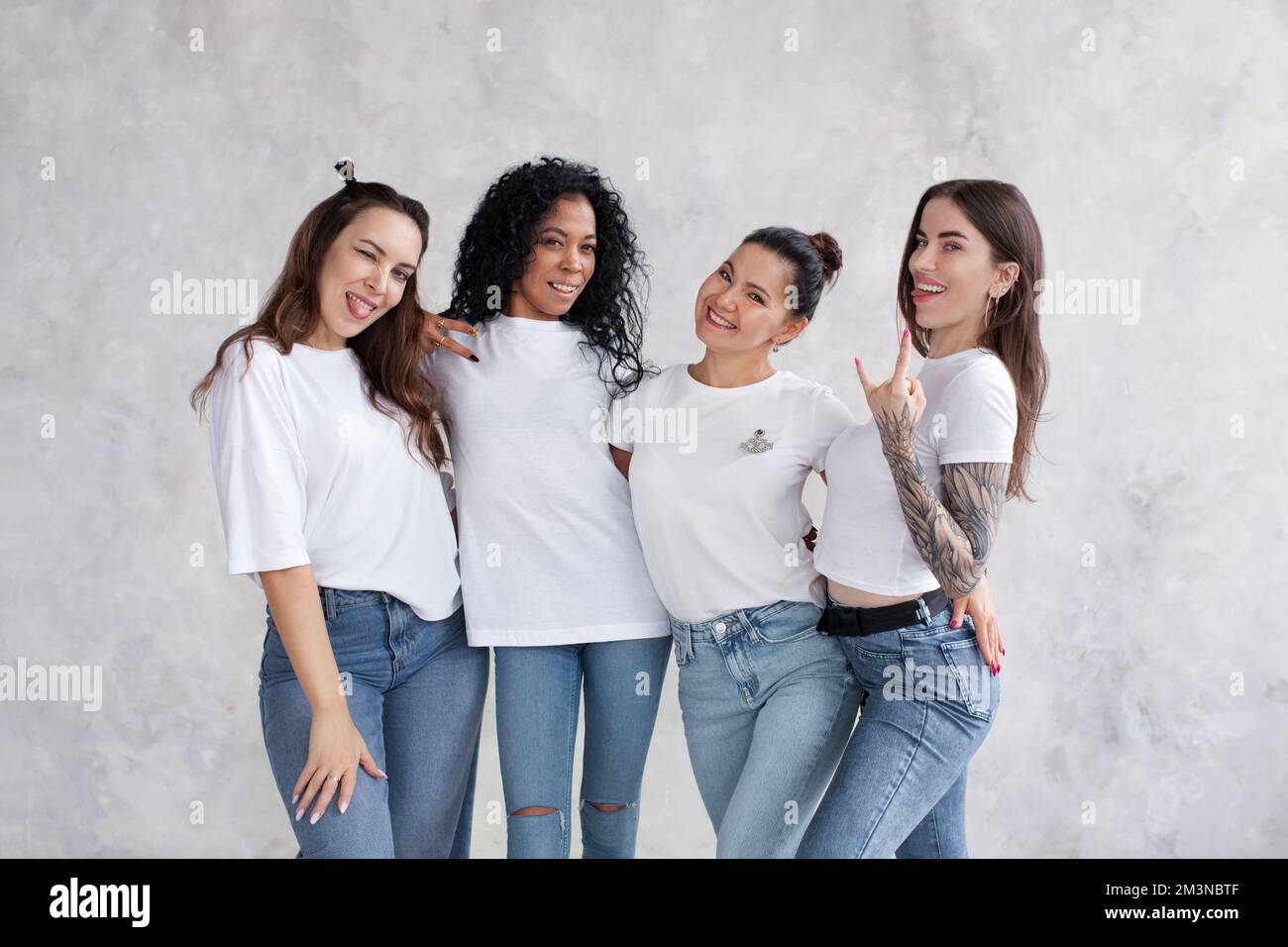 Group young women stand isolated against wall background, looking at ...