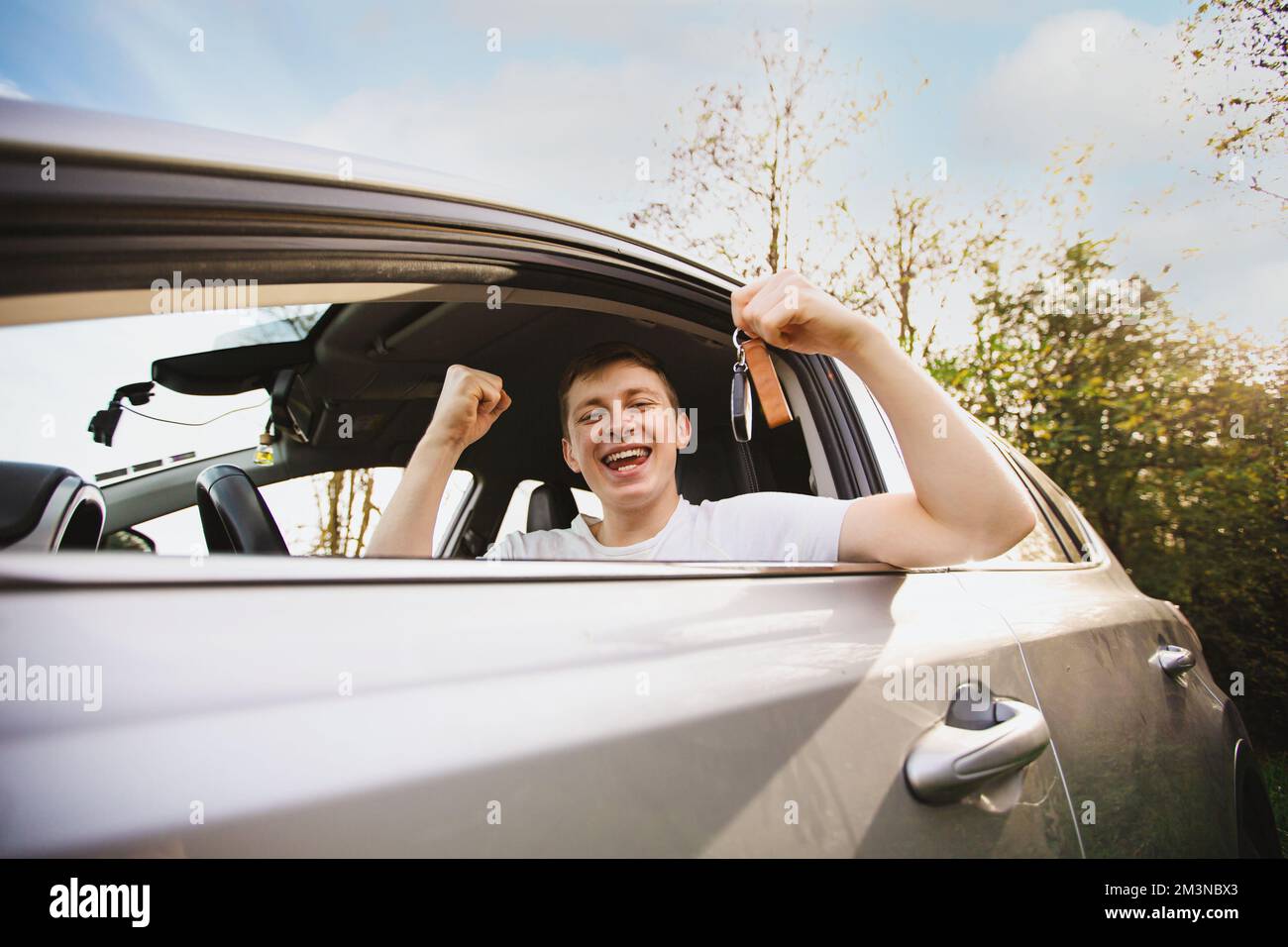 Happy Novice driver keeps fist up tight looking out of the driver ...