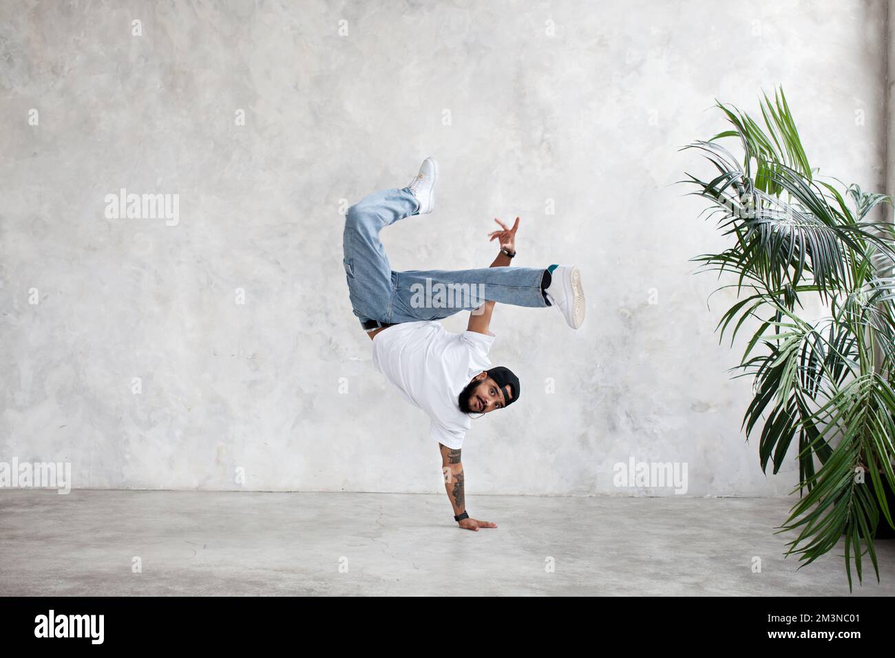 B-Boy performing one handed freeze. Guy breakdancer stands on arm and ...