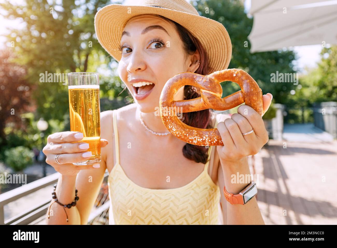 Tipsy girl with a glass of beer and a traditional German snack pretzel ...
