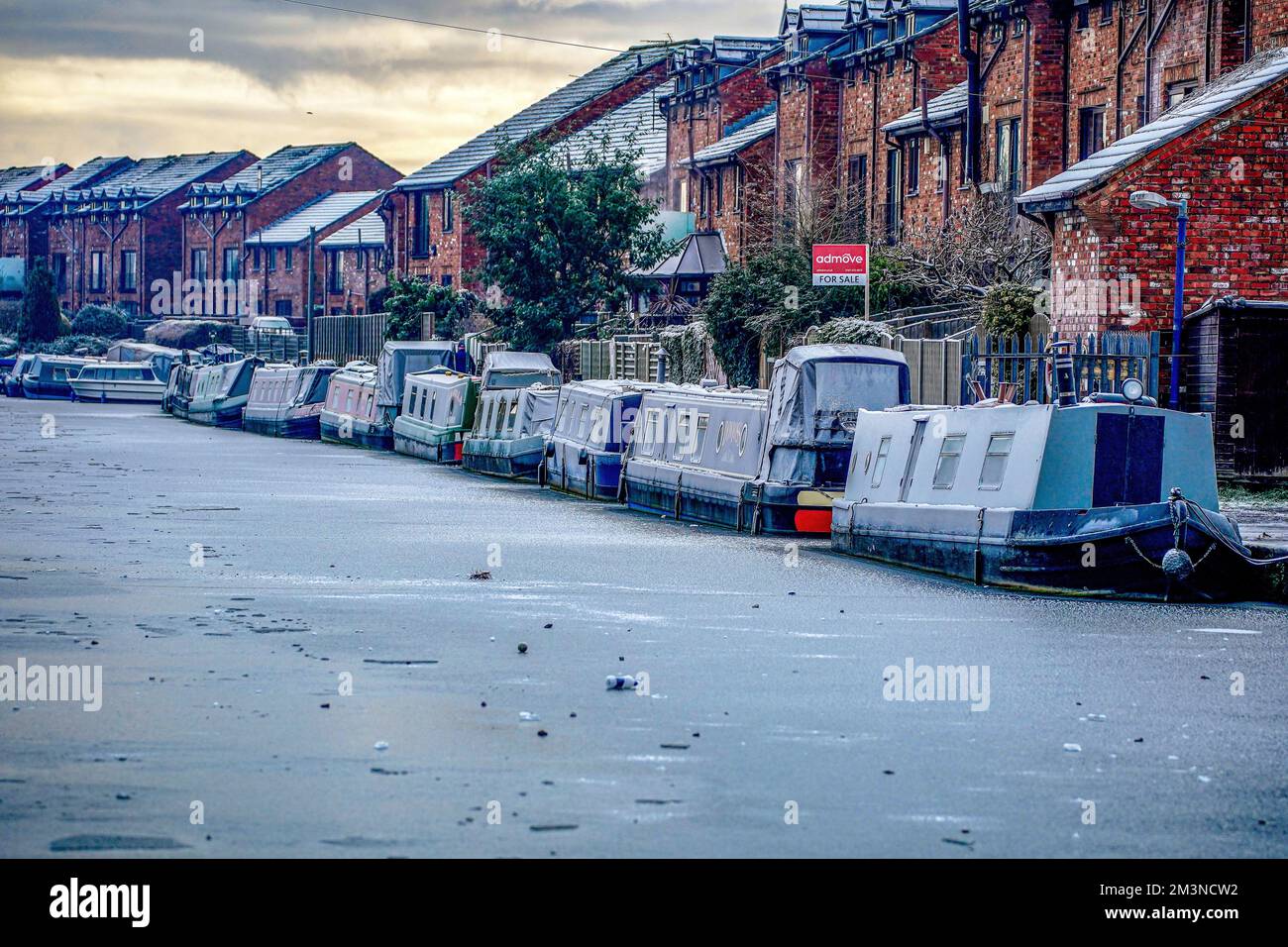 Moored canal boats on a frozen Bridgewater canal in Lymm, Cheshire ...