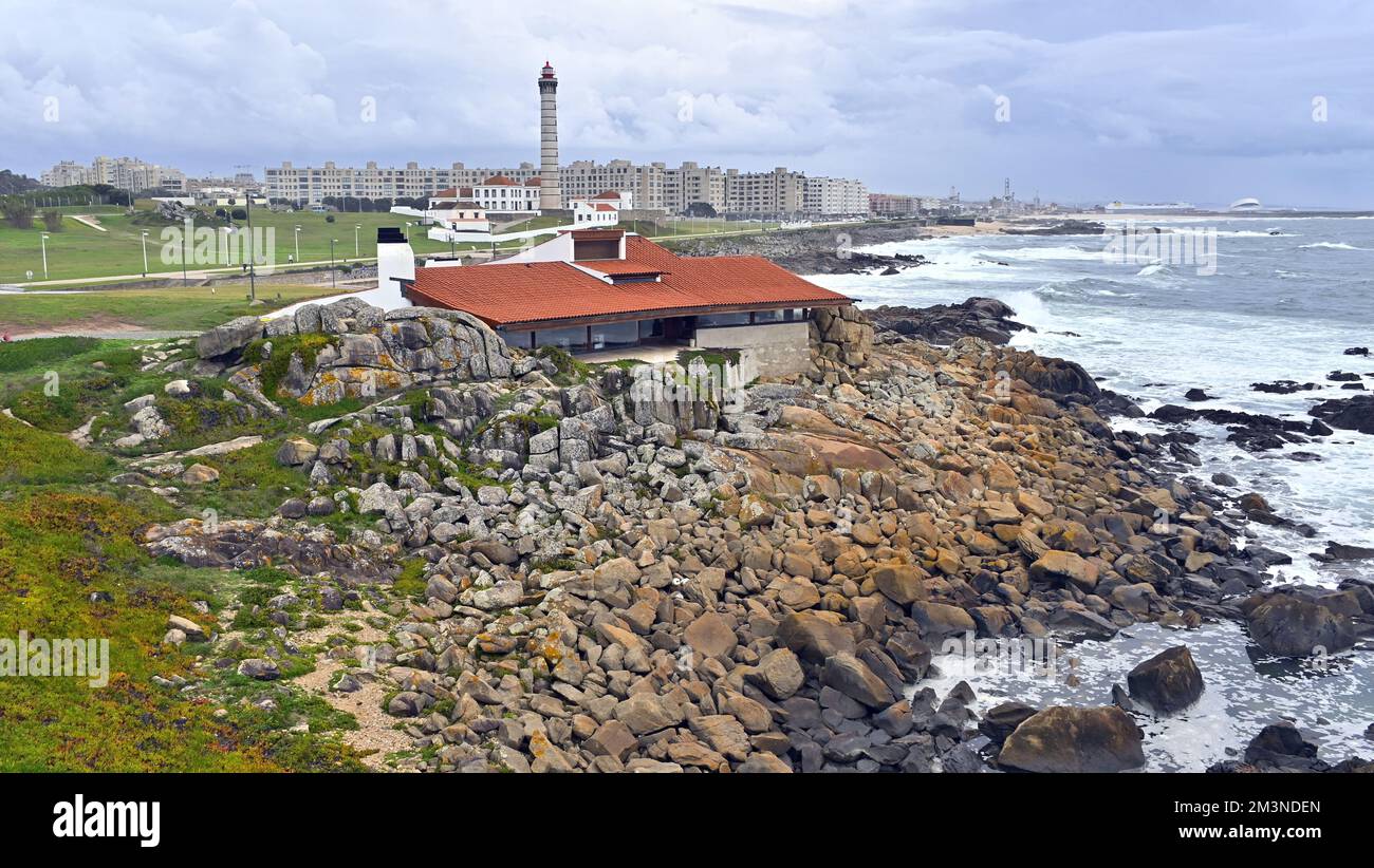 The scenic Leca Lighthouse on the seashore in the background of a red-roofed building Stock ...