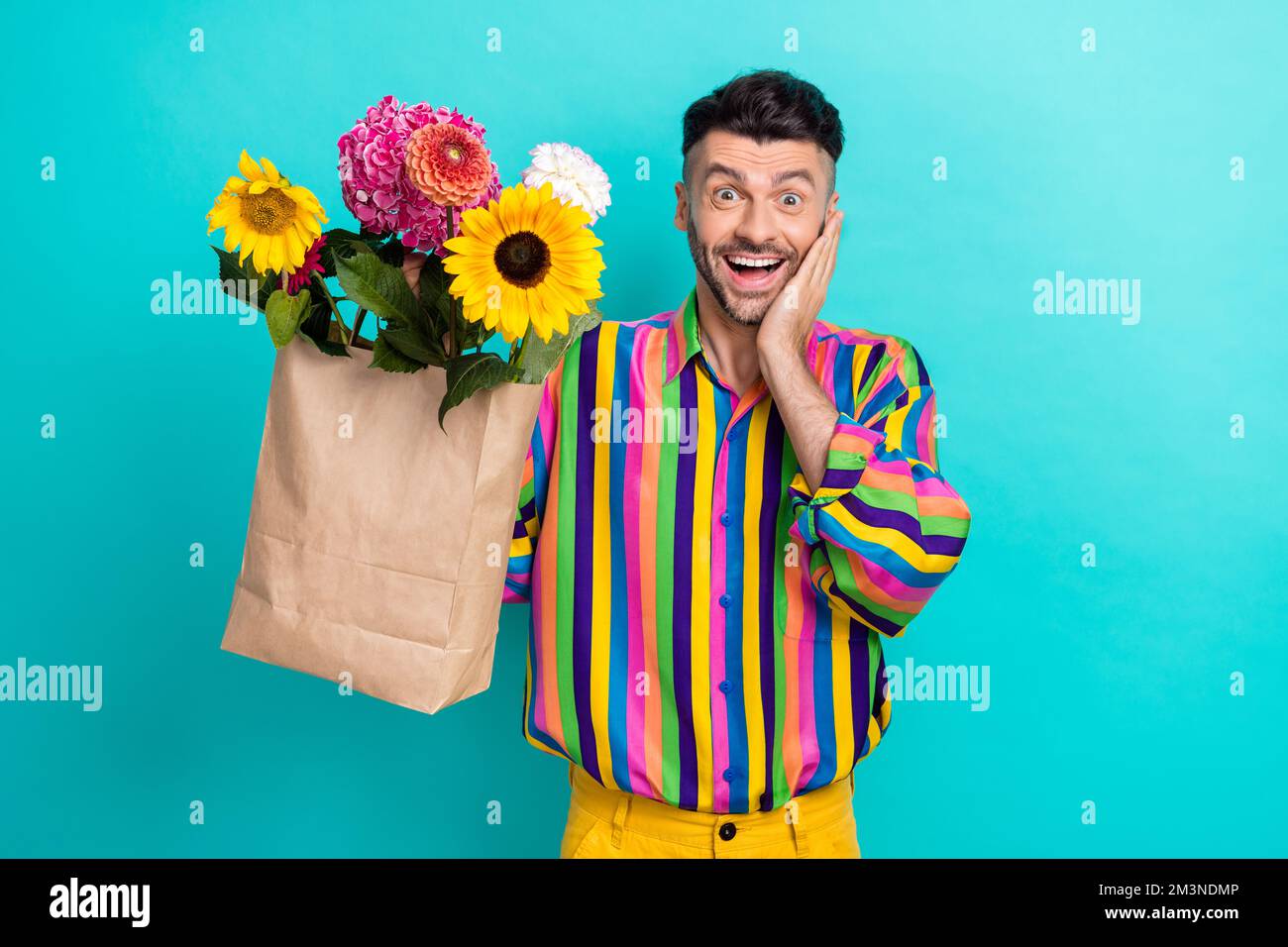 Portrait of positive impressed guy arm touch cheek hold bunch flowers ...