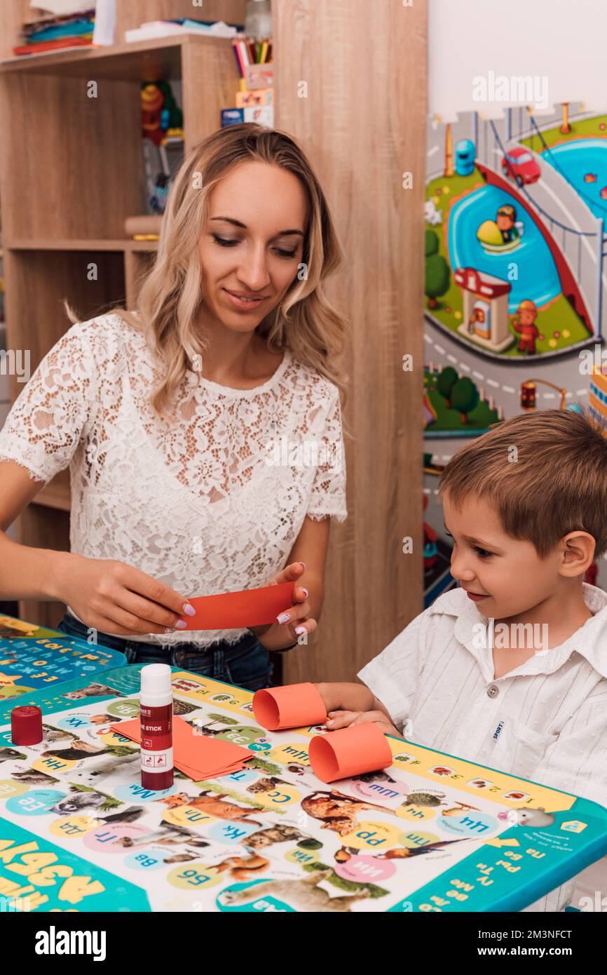 Mother and son sit and make a craft from paper and glue, lesson ...