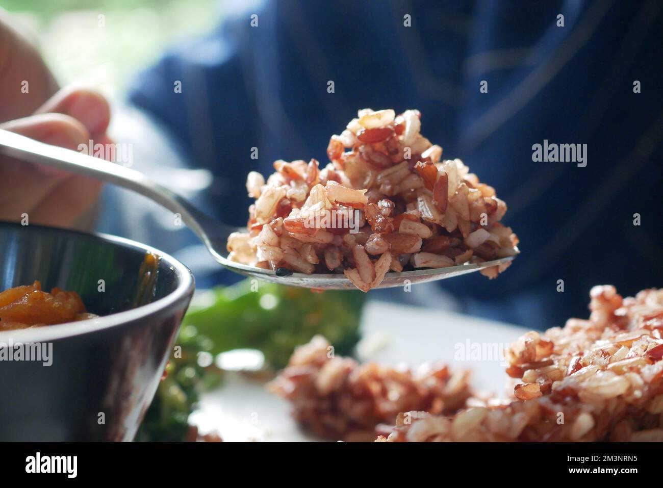 women eating cooked red rice Stock Photo - Alamy