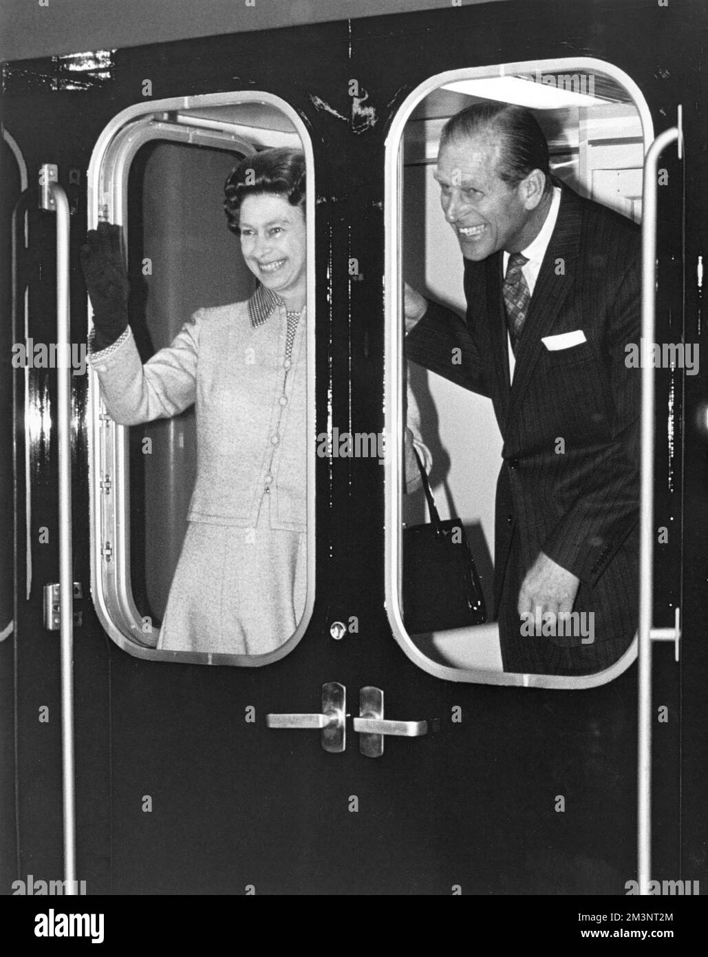 Queen Elizabeth II and the Duke of Edinburgh waving from a train in the ...