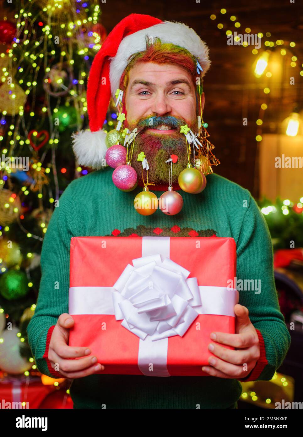 Happy man in Santa hat with decorated beard and Christmas gift. New ...