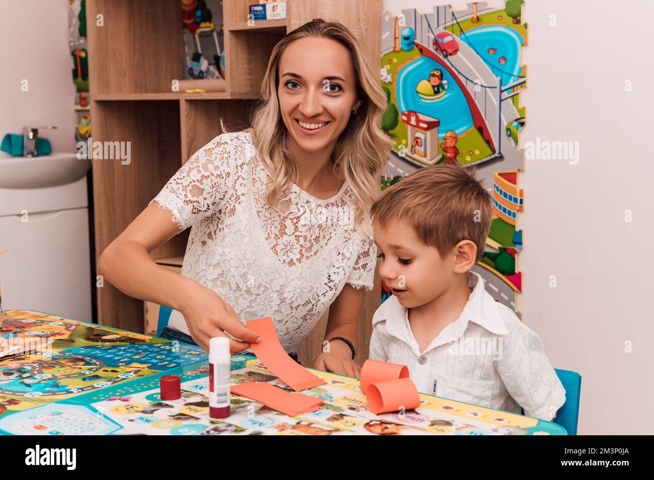 Mother and son sit and make a craft from paper and glue, lesson ...