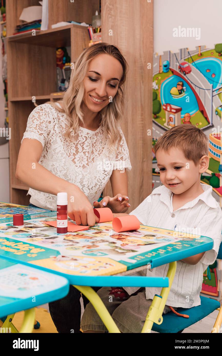 Mother and son sit and make a craft from paper and glue, lesson ...