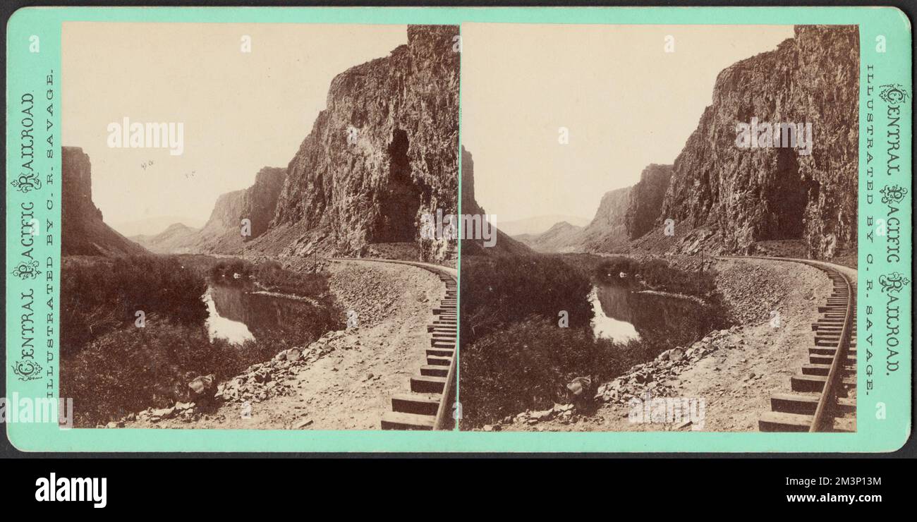 A railroad track curving through rock formations, a body of water to ...