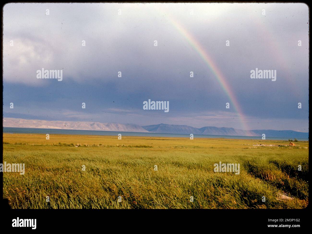 Rainbow over field with water and mountains in distance, likely Utah ...