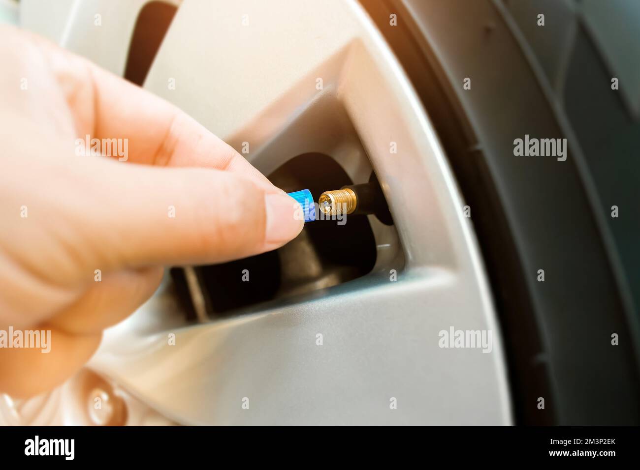 The driver is putting on the wheel tire valve cap of a car after ...