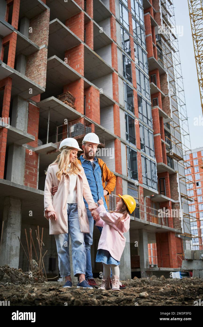 Happy family homeowners standing on the street at construction site ...