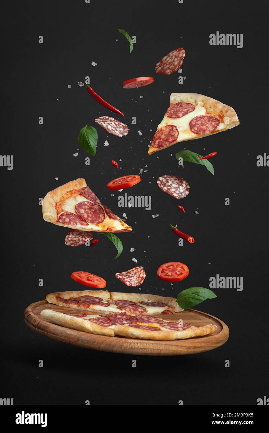 flying pizza with ingredients on a black background Stock Photo - Alamy