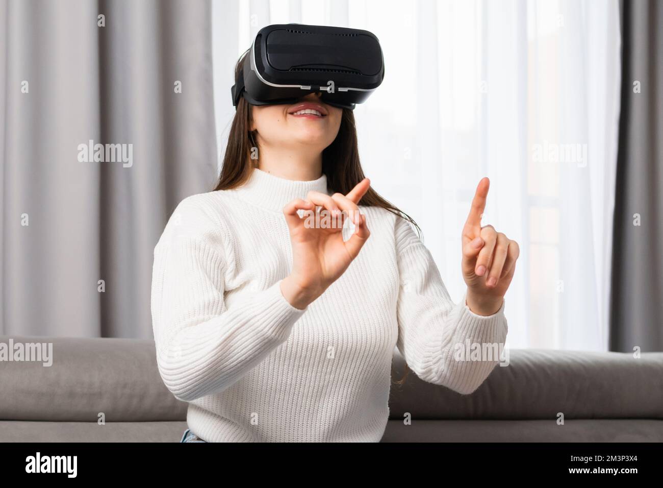 Happy young woman using a virtual reality headset and pushing invisible ...