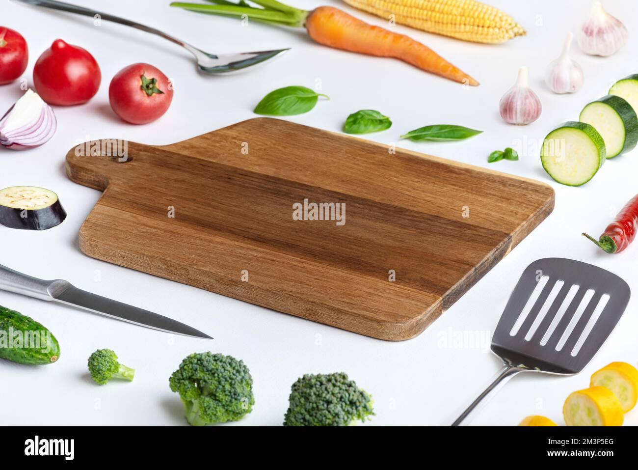 culinary white background with wooden board, metal utensils and ...