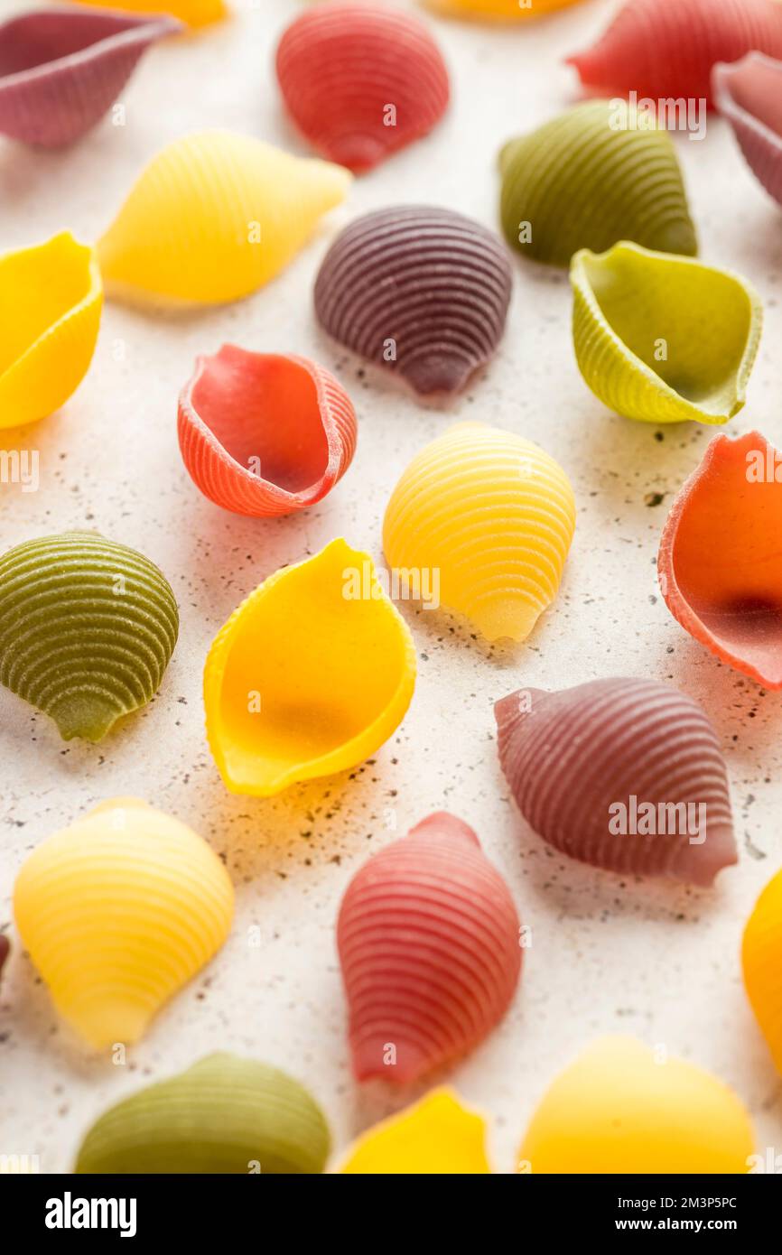 Top view of five colors pasta shells on white stone background. Pasta ...