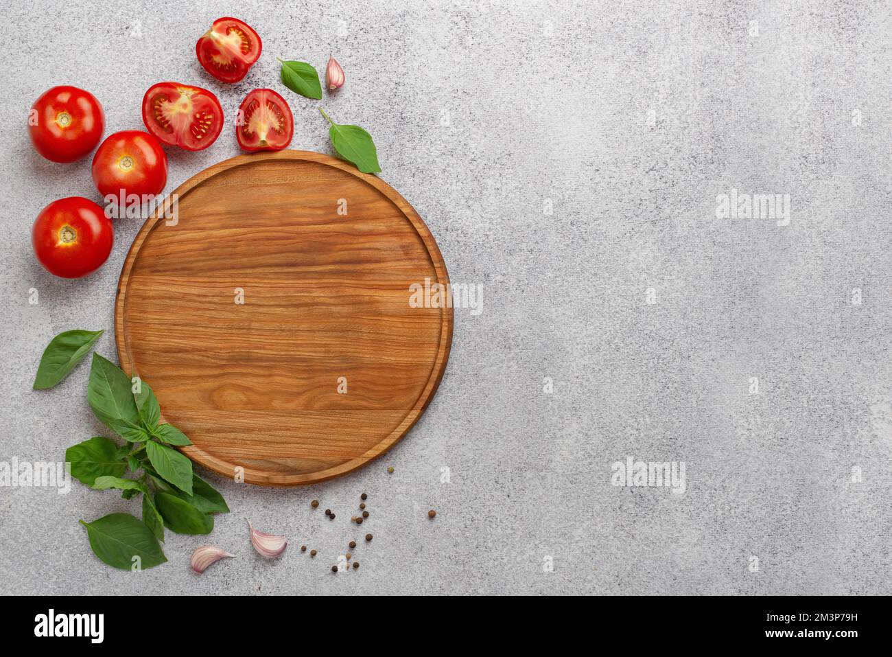 light culinary background with round wooden board, tomatoes and basil ...