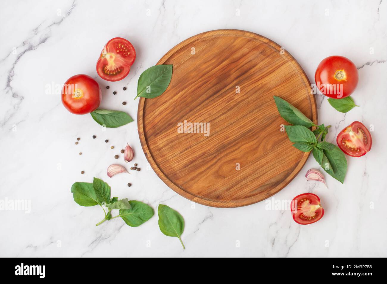 light culinary background with round wooden board, tomatoes and basil ...