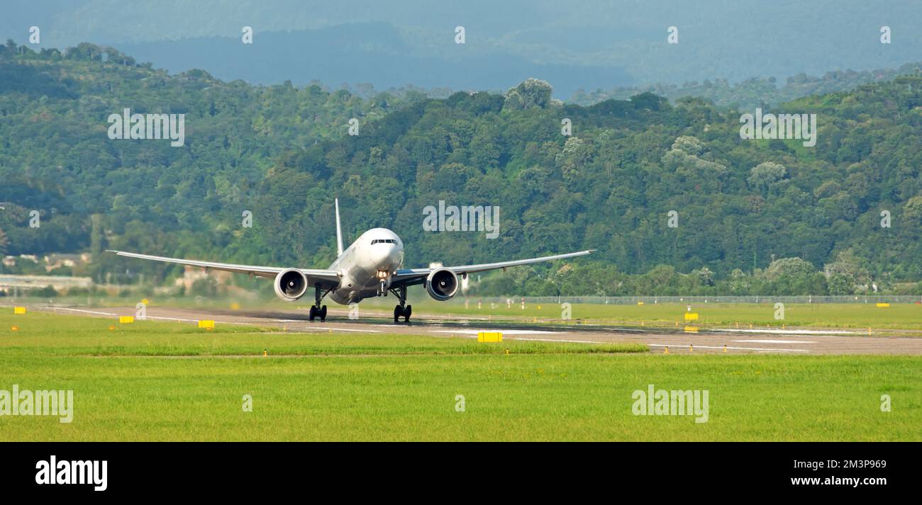 Panoramic wide view of a landing plane on the runway in a mountainous ...