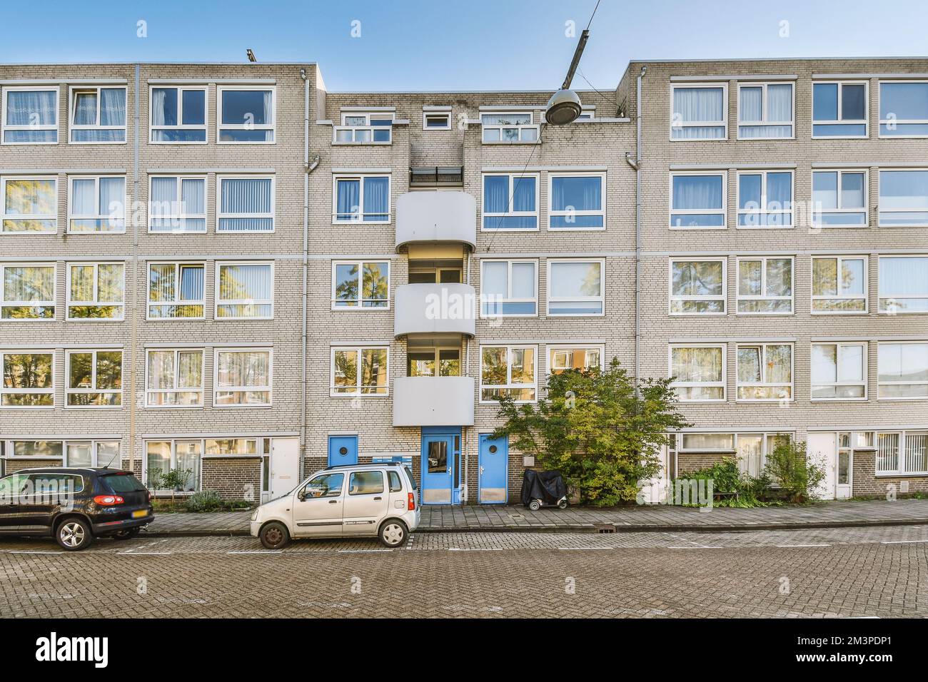 an apartment building with cars parked on the street next to it and two ...