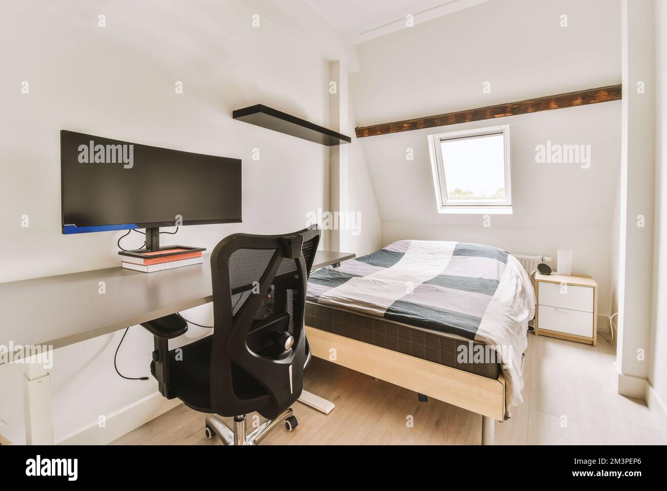 a bedroom with a bed, desk and television set up on the wall in front ...