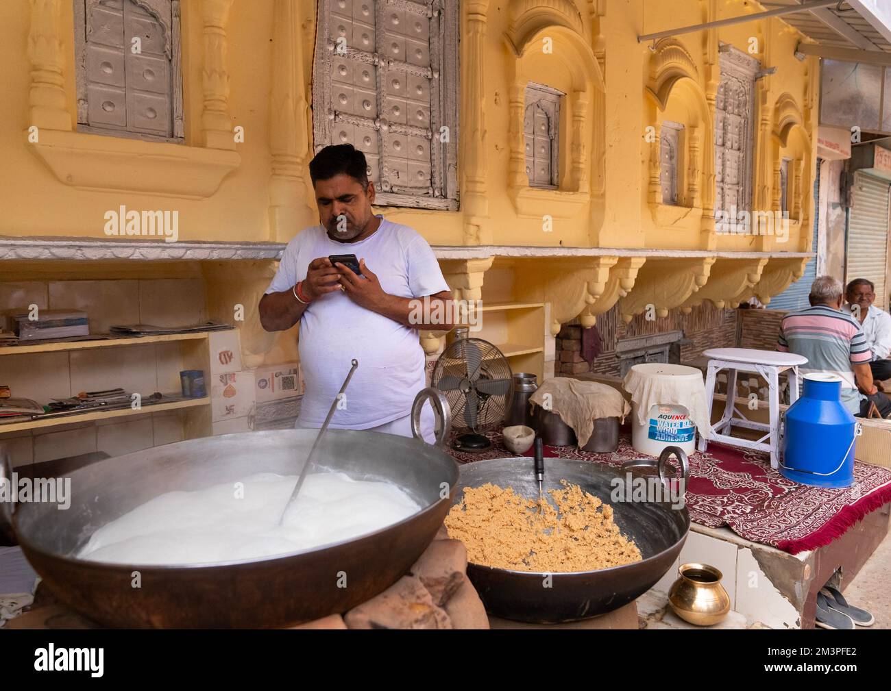 Indian man speaking on the phone while making sweets, Rajasthan ...