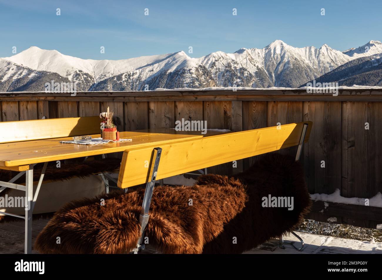 Table and benches with skins in a mountain cafe overlooking the snow ...