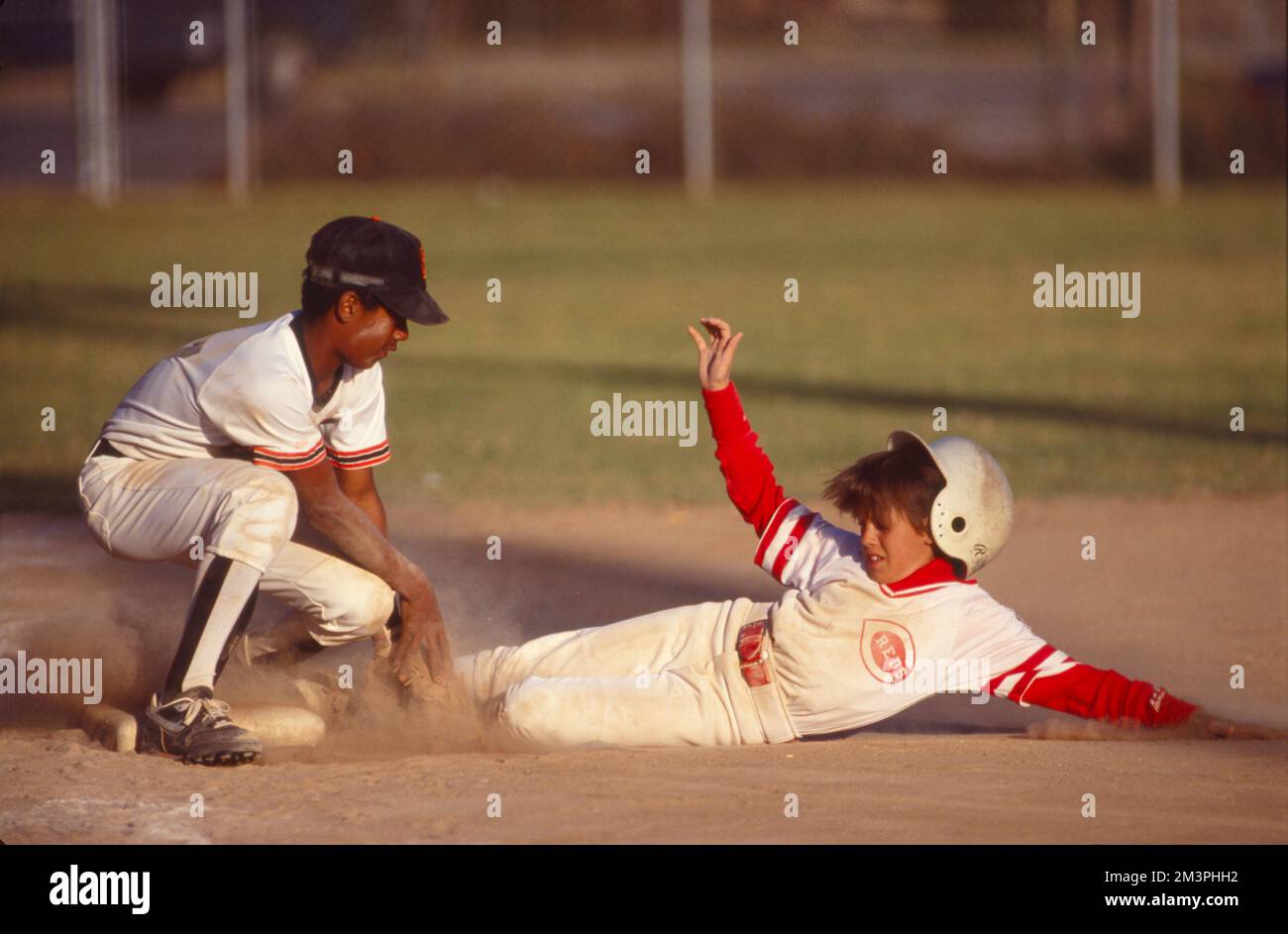 Boy sliding into baseball base while other boy tags him out Stock Photo ...