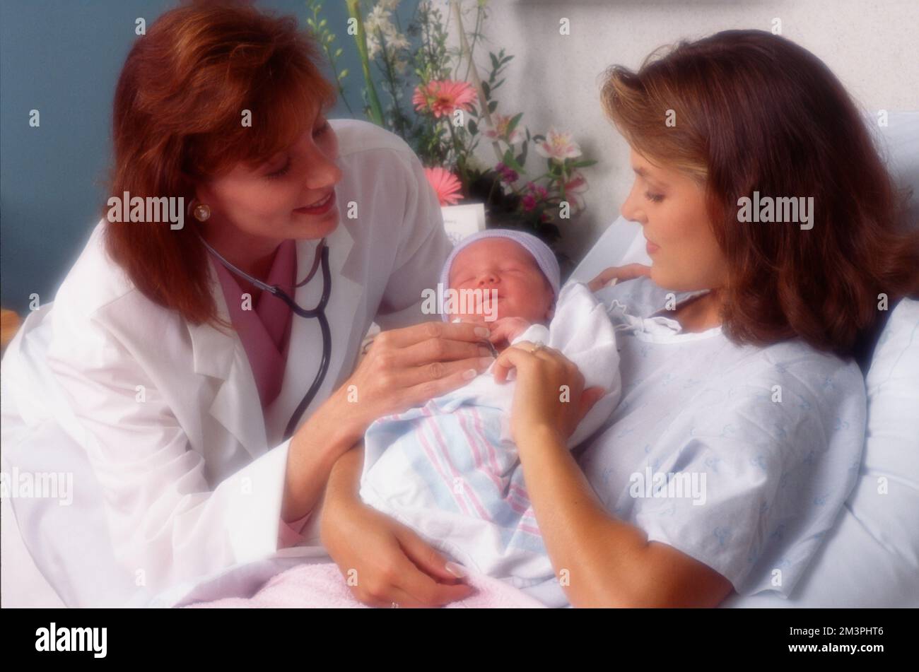 Female doctor at bedside of newborn mother and baby listening to its ...