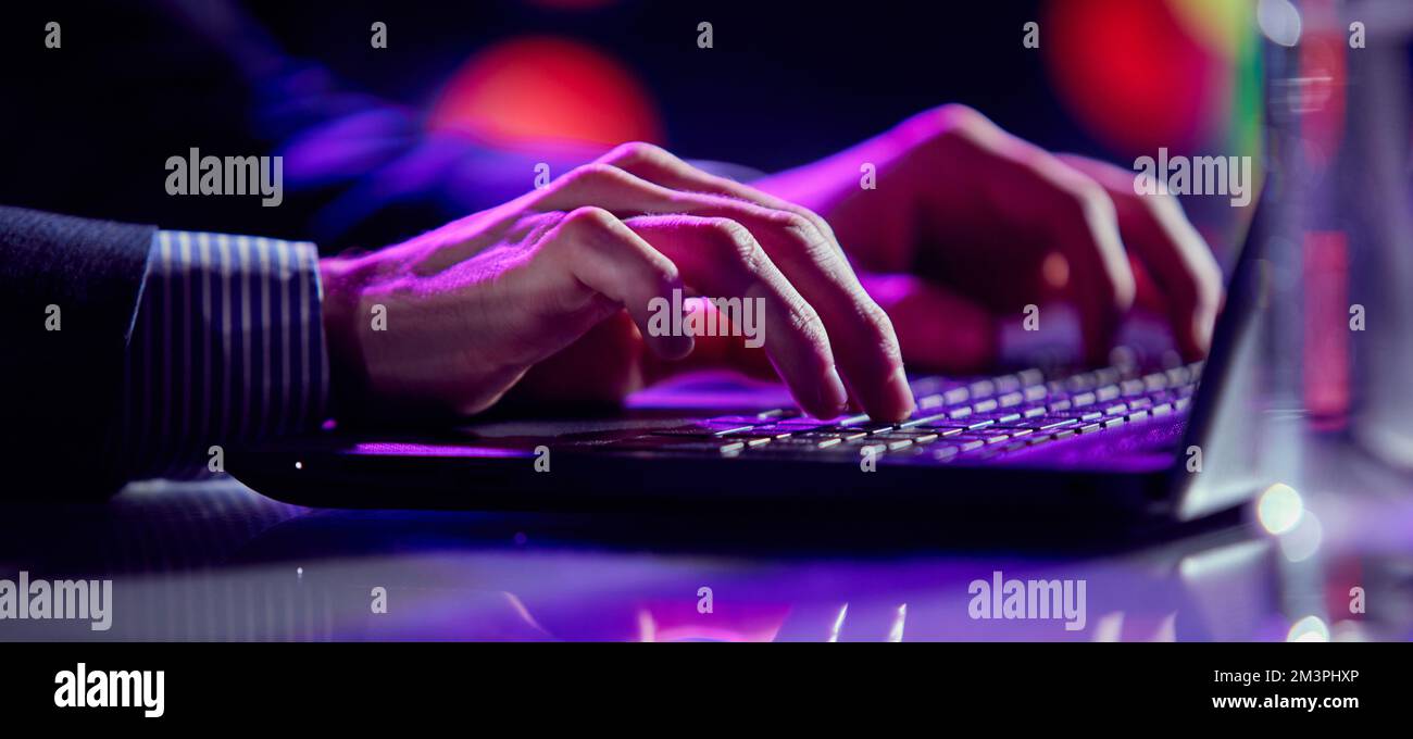 Closeup of male hands typing on laptop keyboard at evening time. Cool ...