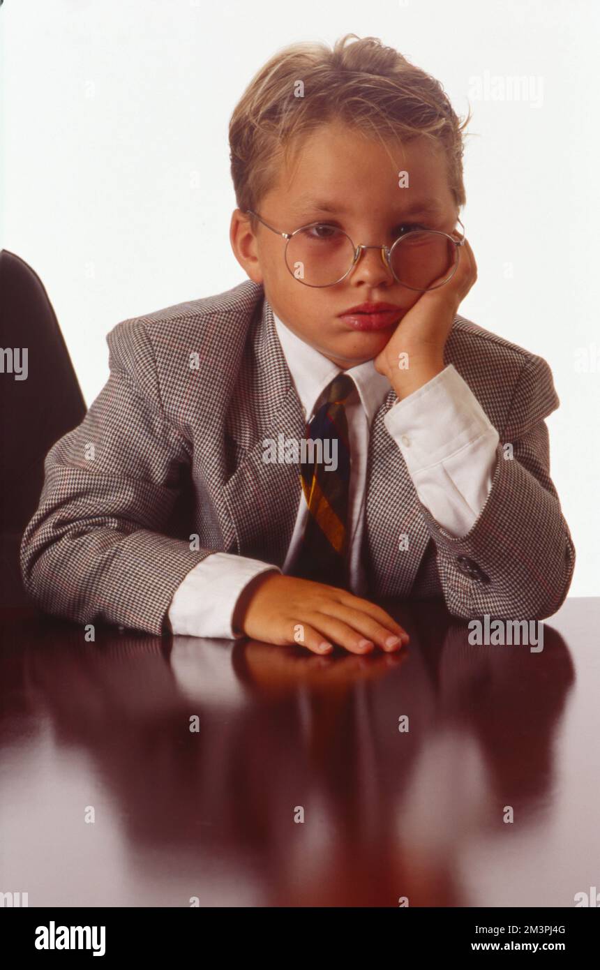 Young boy dressed in a business suit with head in hand looking dejected ...